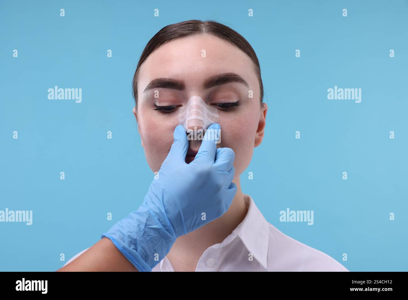 Doctor checking patient's nose after plastic surgery operation on light ...