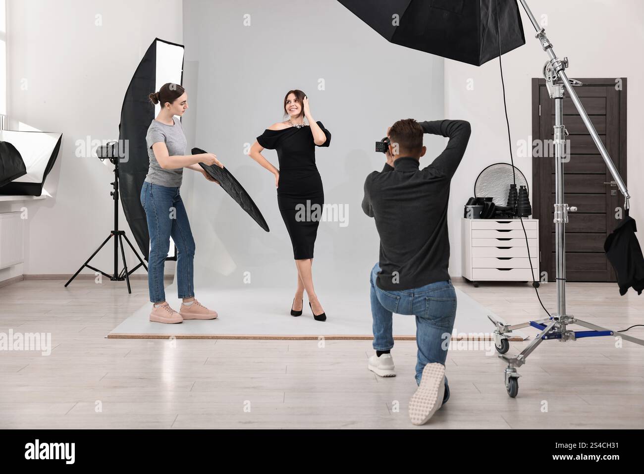 Photographer and assistant working with model in professional photo ...