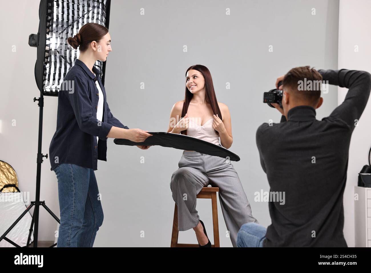 Photographer and assistant working with model in professional photo ...