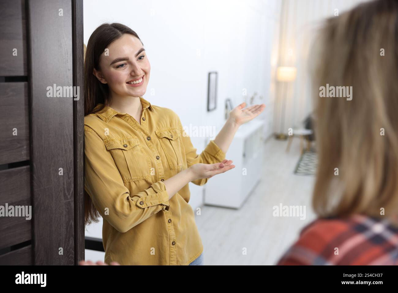 Happy woman welcoming friend to her apartment Stock Photo - Alamy