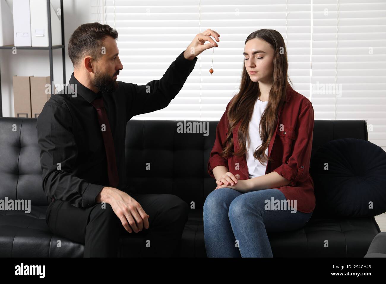 Psychologist using pendulum while working with patient during hypnosis ...