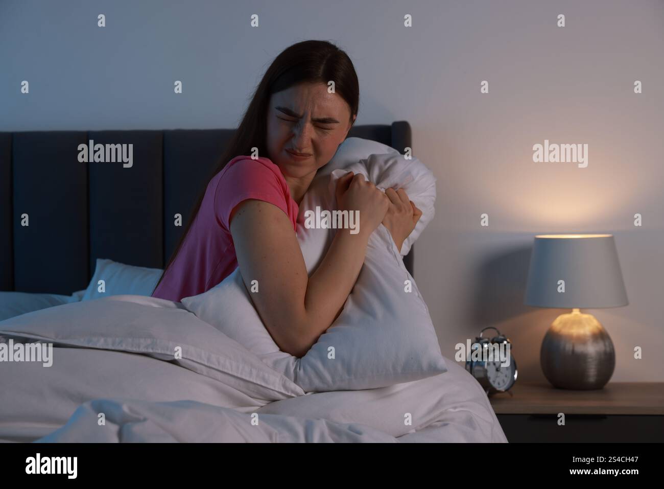 Fear of darkness. Scared young woman on bed in room at night Stock ...