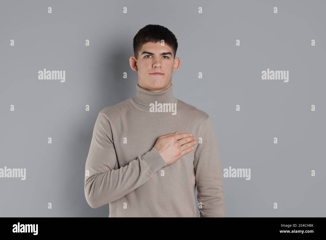 Man showing oath gesture on grey background Stock Photo - Alamy
