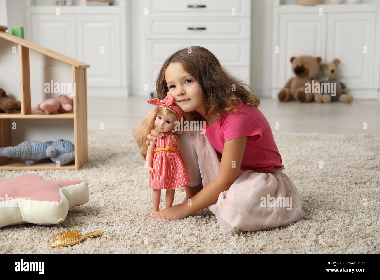 Cute little girl playing with her doll on floor at home Stock Photo - Alamy