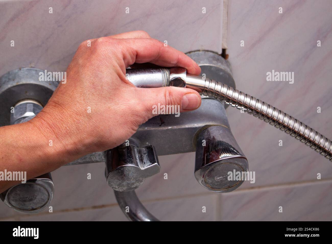 Woman changing broken shower hose in bathroom. Female plumber hands ...