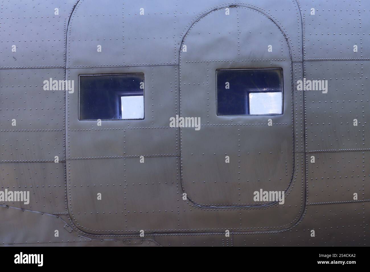 The side of an old airplane with emergency exit and illuminators ...