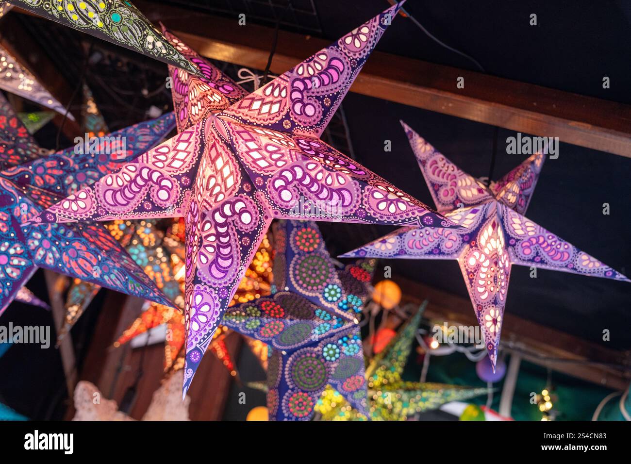 Colorful purple paper stars hanging from the eaves of a Christmas ...