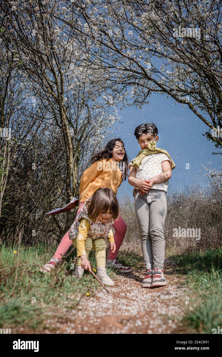 three happy children standing under the blooming trees Stock Photo - Alamy