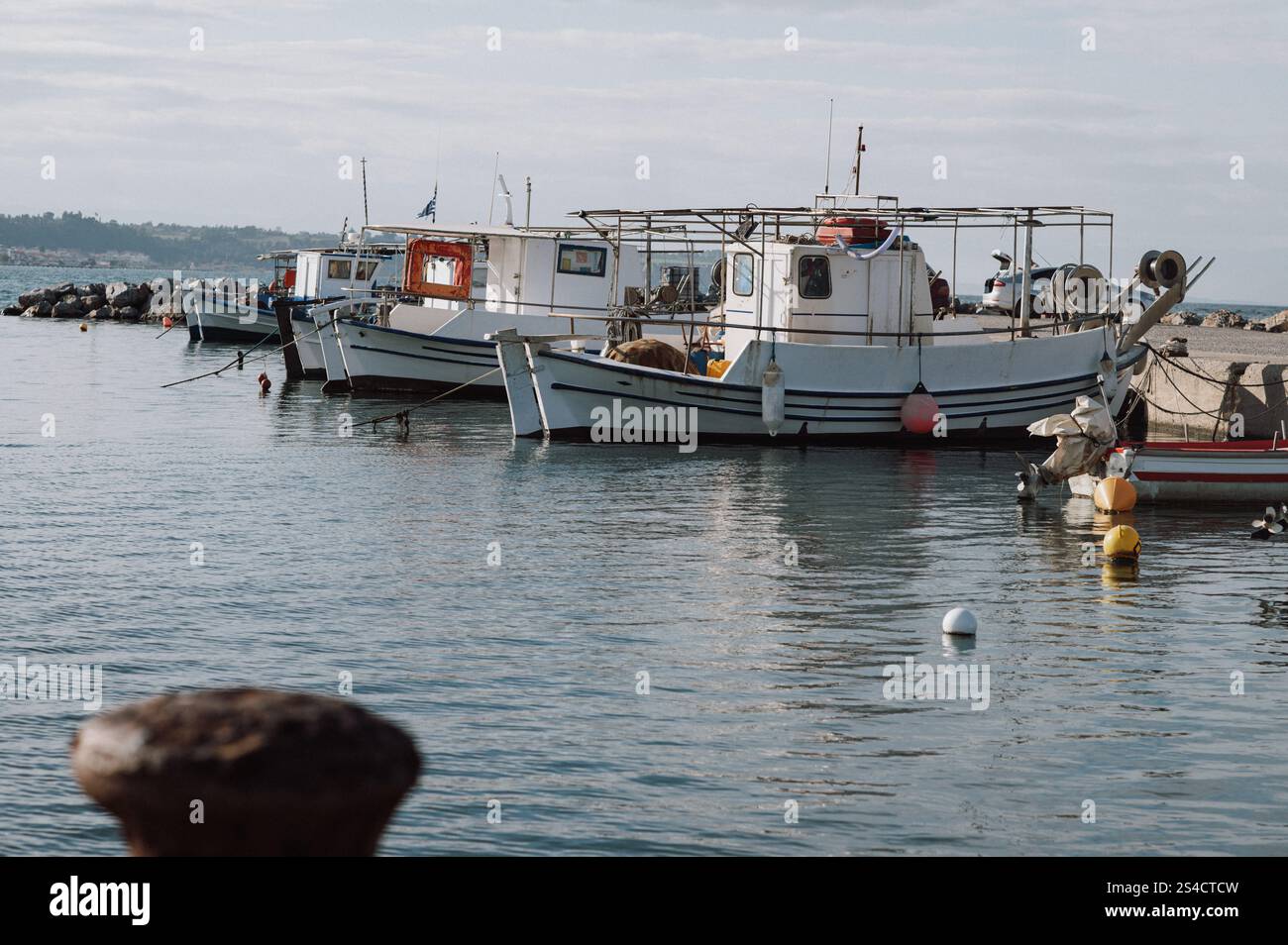 Fishing boats anchored at a pier in a small Greek village, gently ...