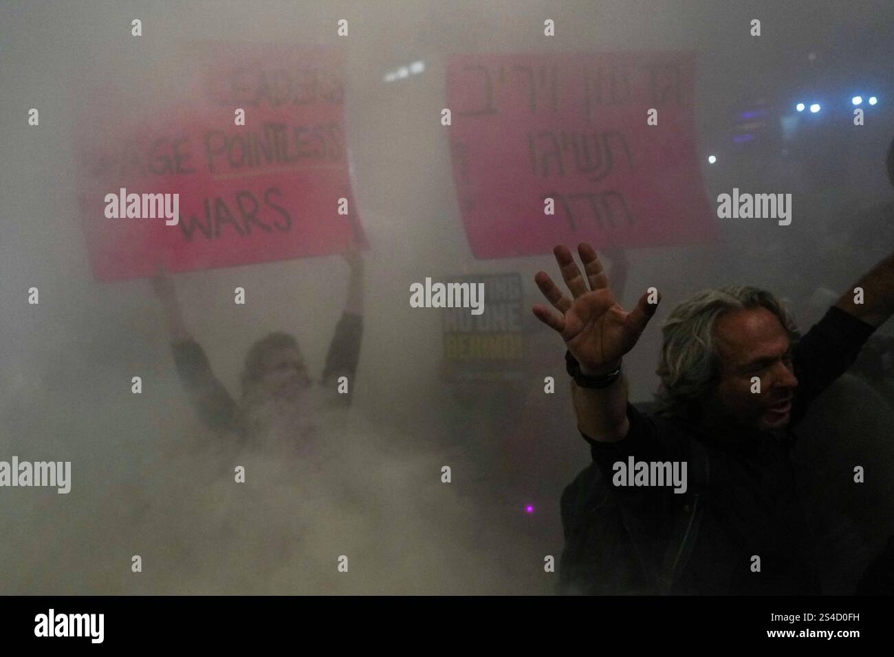 Demonstrators hold signs during a protest calling for the immediate ...