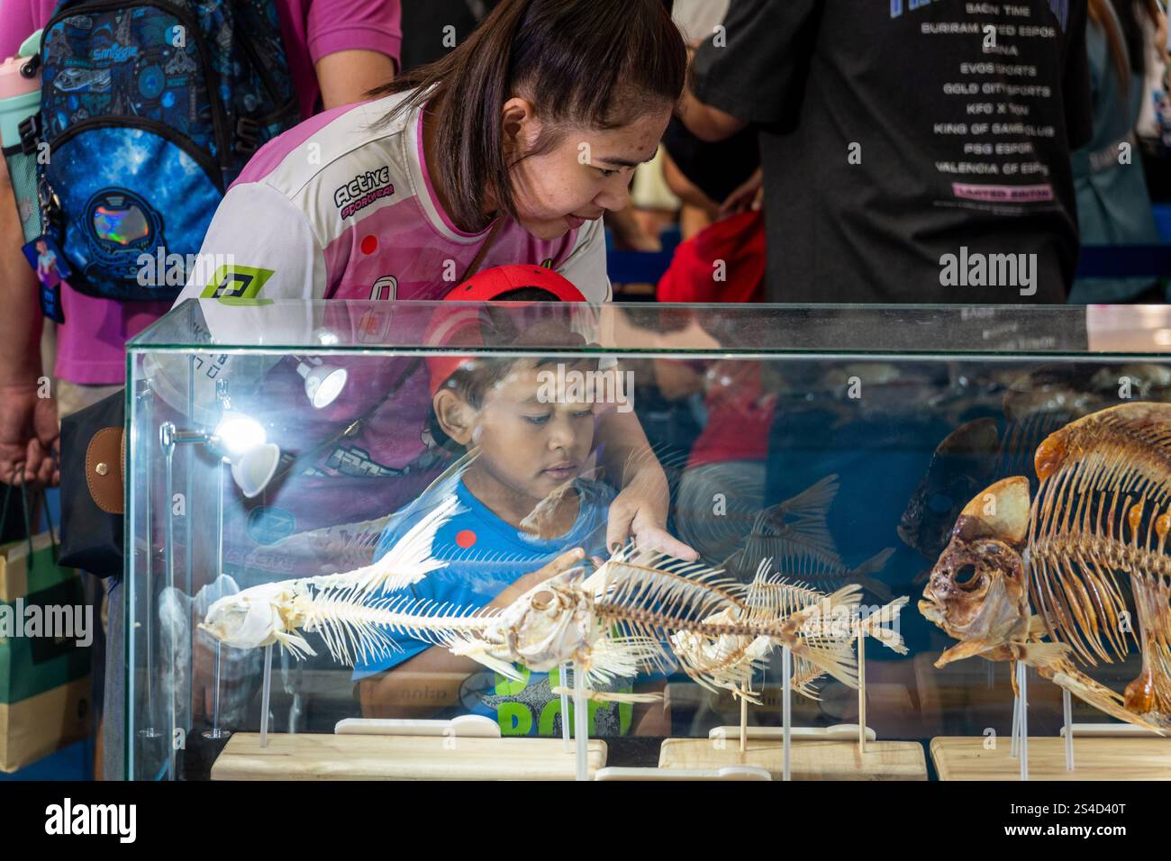 A mother is seen pointing and showing to her son, a part of a fish ...