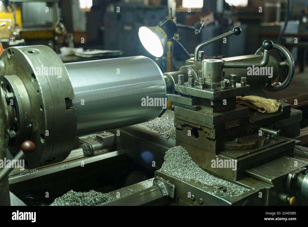 A skilled machinist works diligently at a metal lathe, shaping a ...