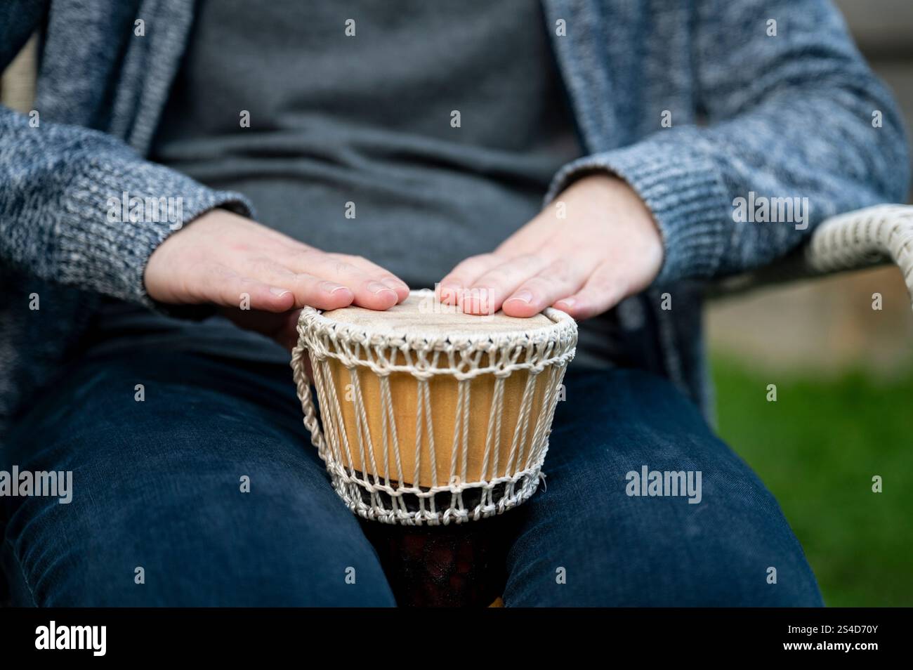 Closeup of hands tapping a small, rope-tuned drum, with the player ...