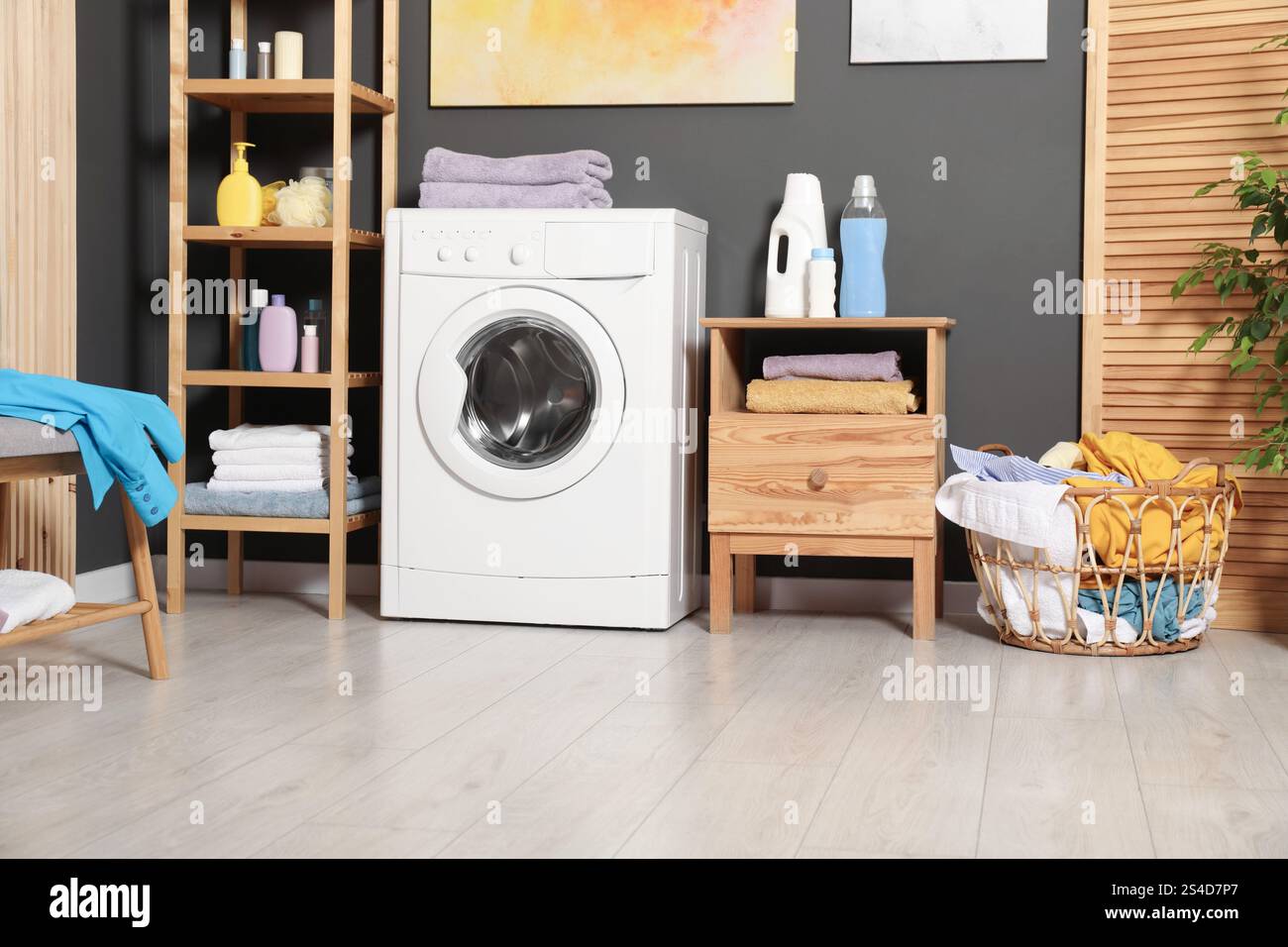 Washing machine, detergents and basket with laundry in room Stock Photo ...