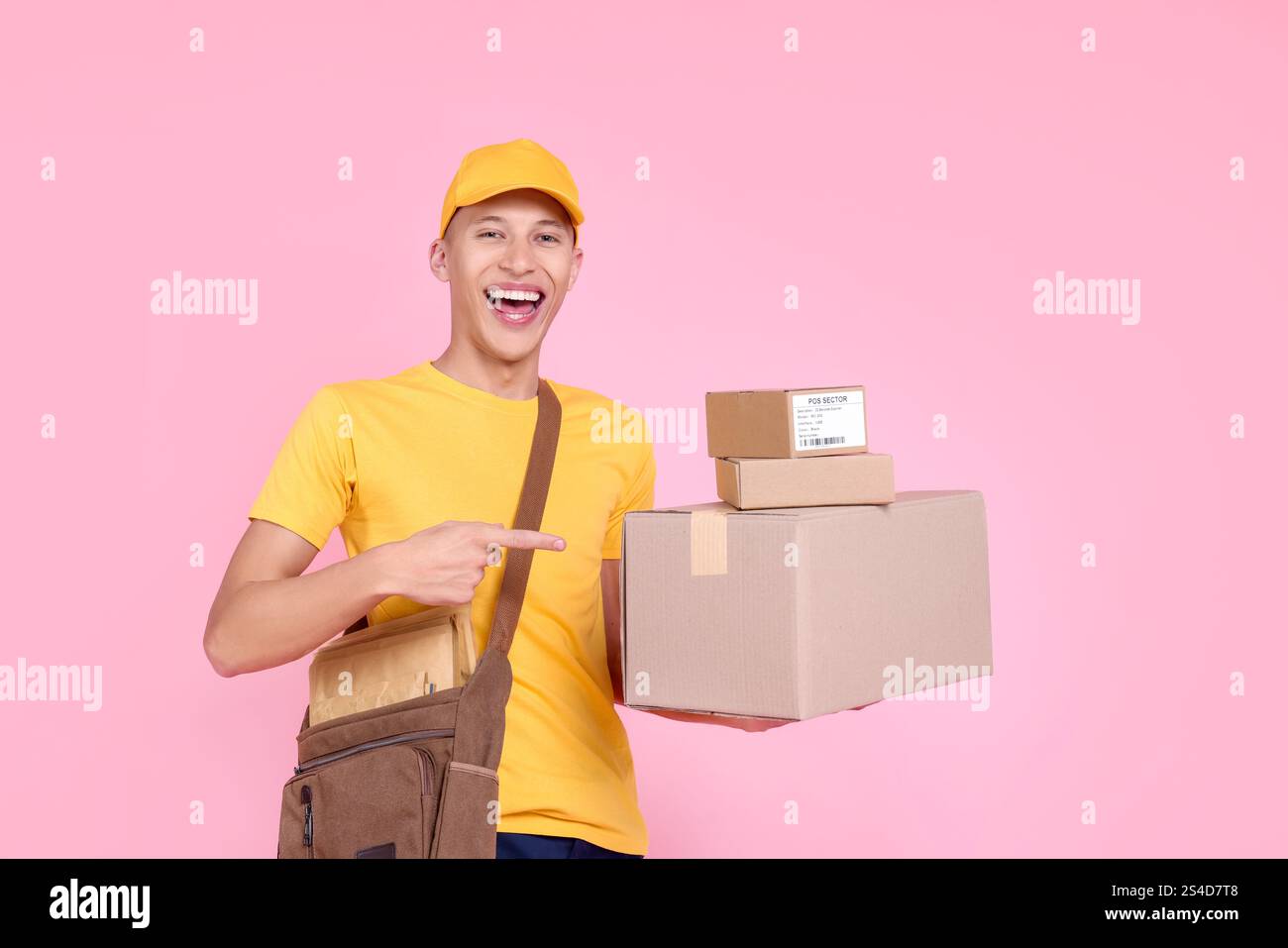 Happy postman pointing at parcels on pink background Stock Photo - Alamy