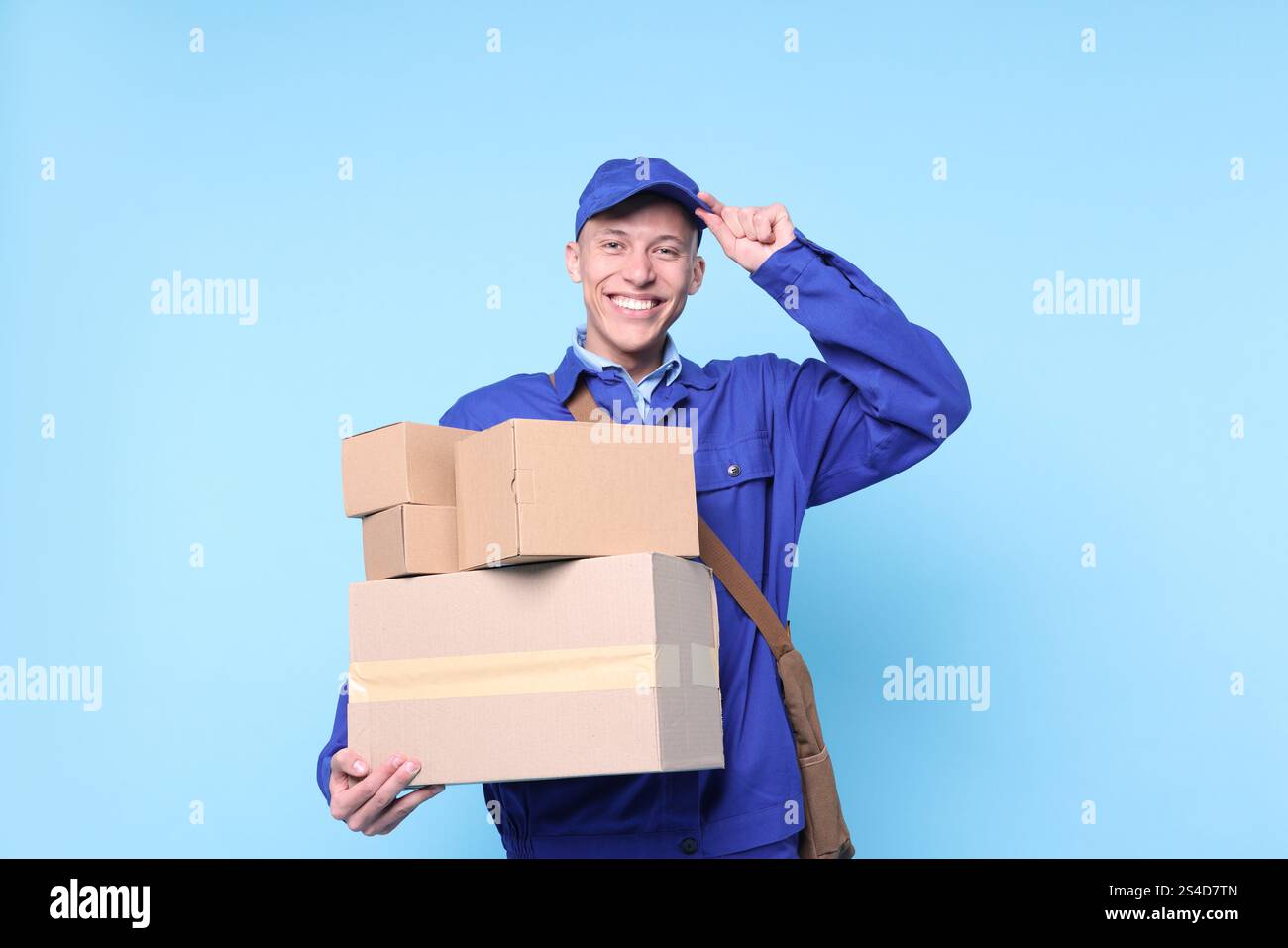 Happy postman with parcels on light blue background Stock Photo - Alamy