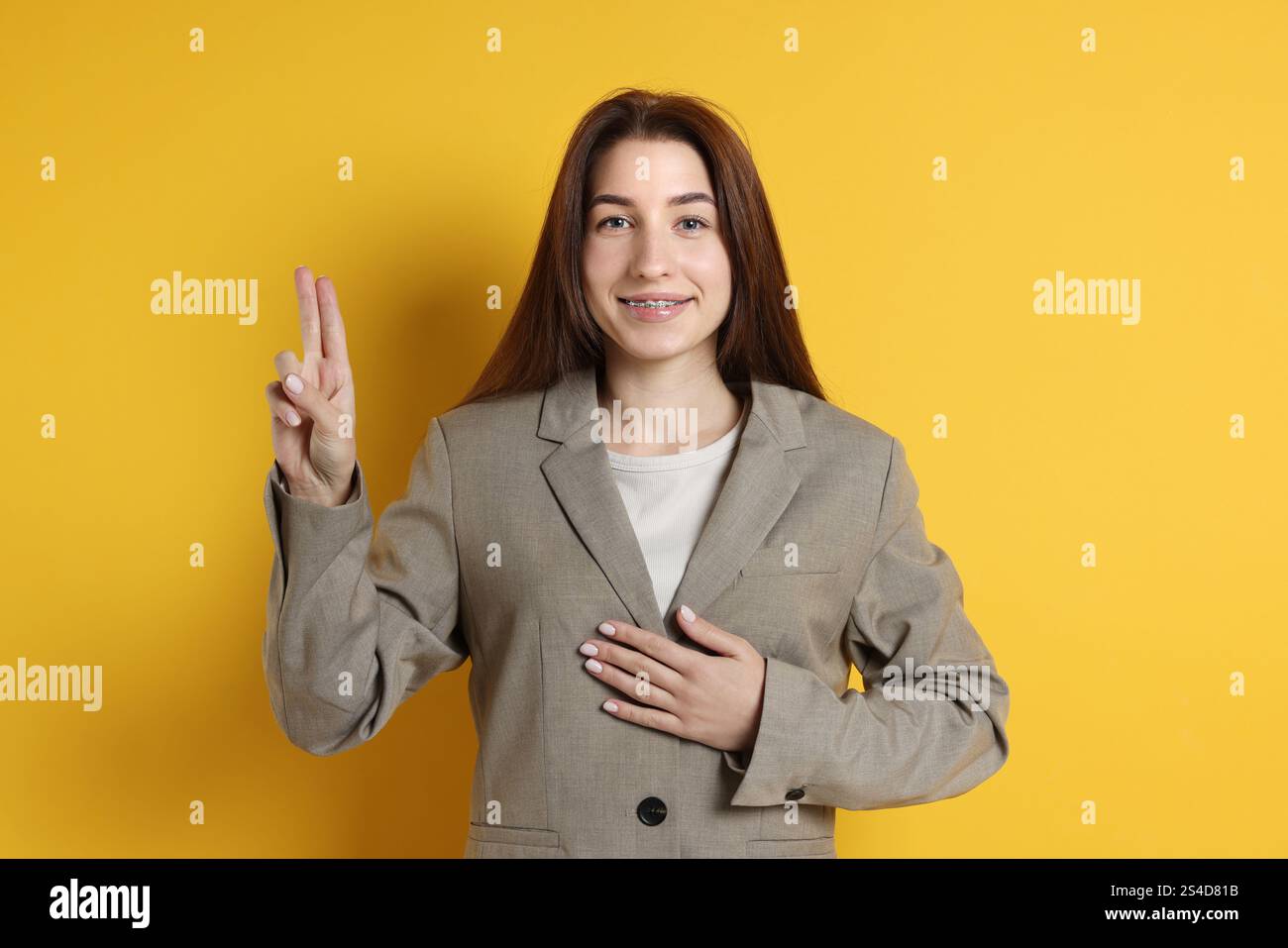 Woman showing oath gesture on orange background. Making promise Stock ...