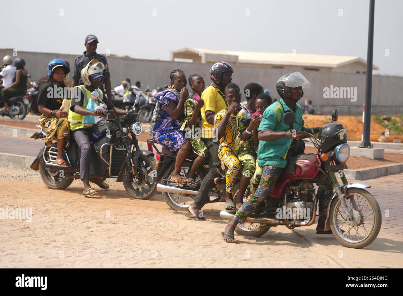 Motorcycle taxi drivers wait for the traffic light to turn green at a ...