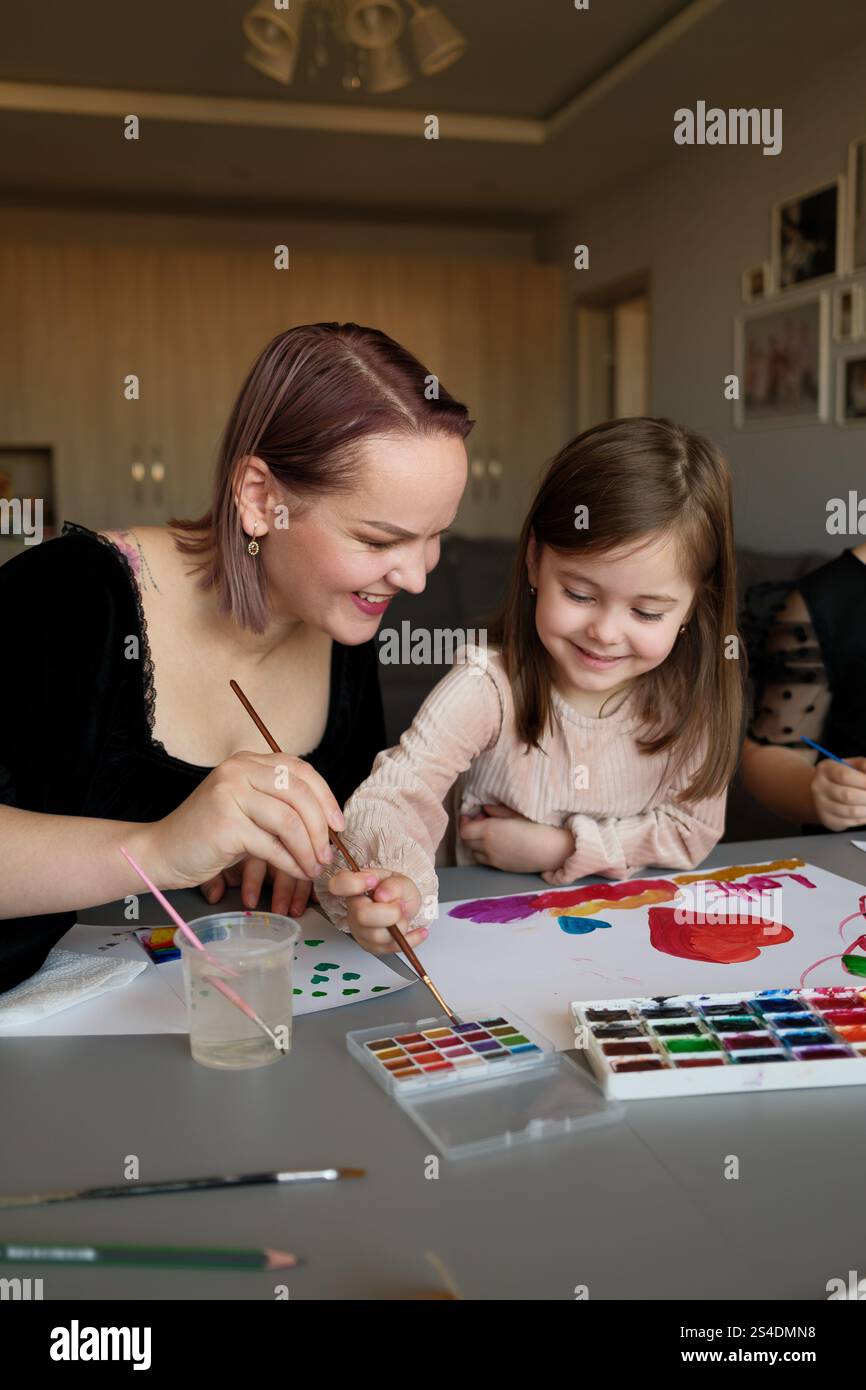 Mother and young girl painting together during a creative arts activity ...