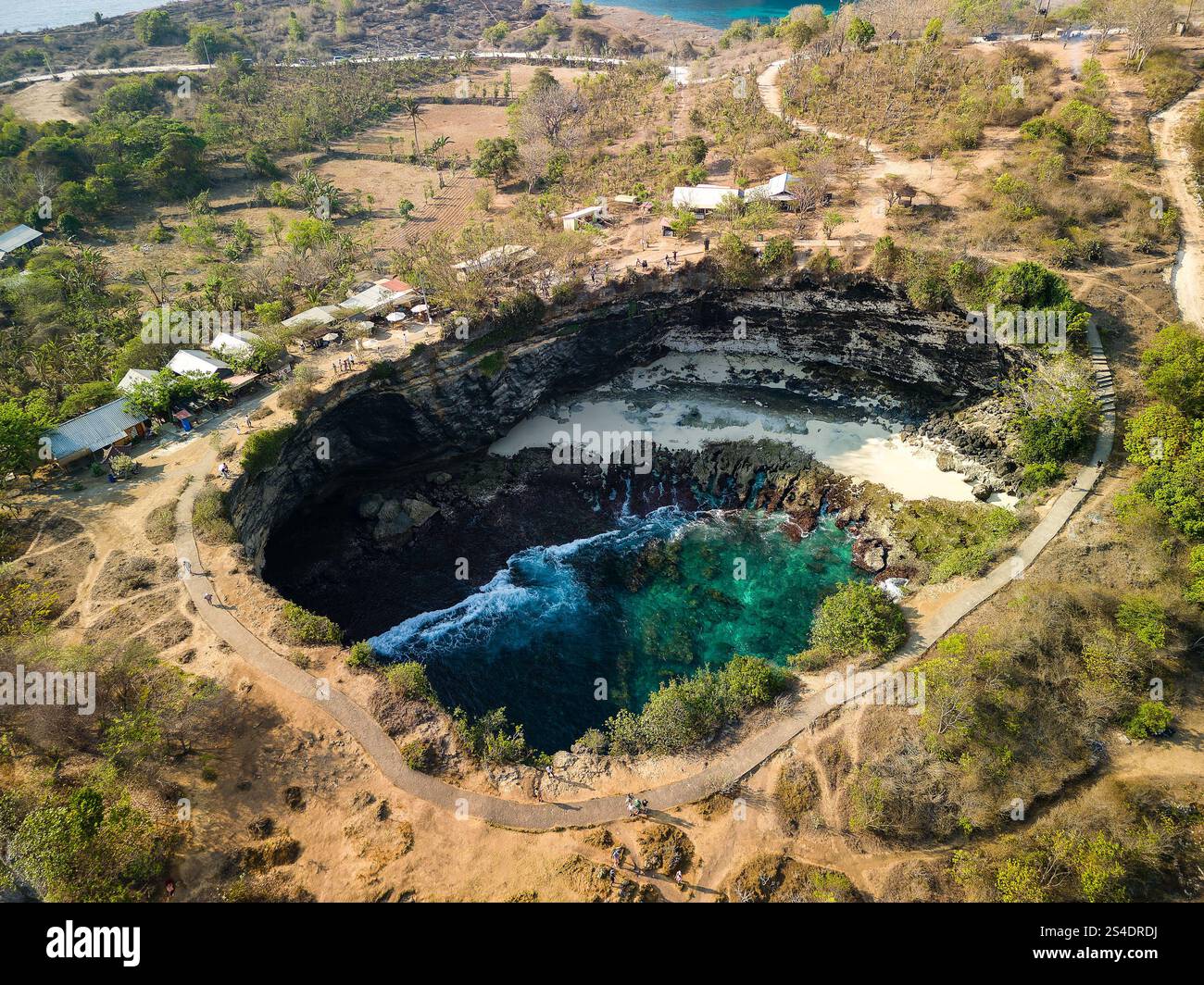 Aerial shot of a tropical beach and ocean waves inside a sinkhole ...