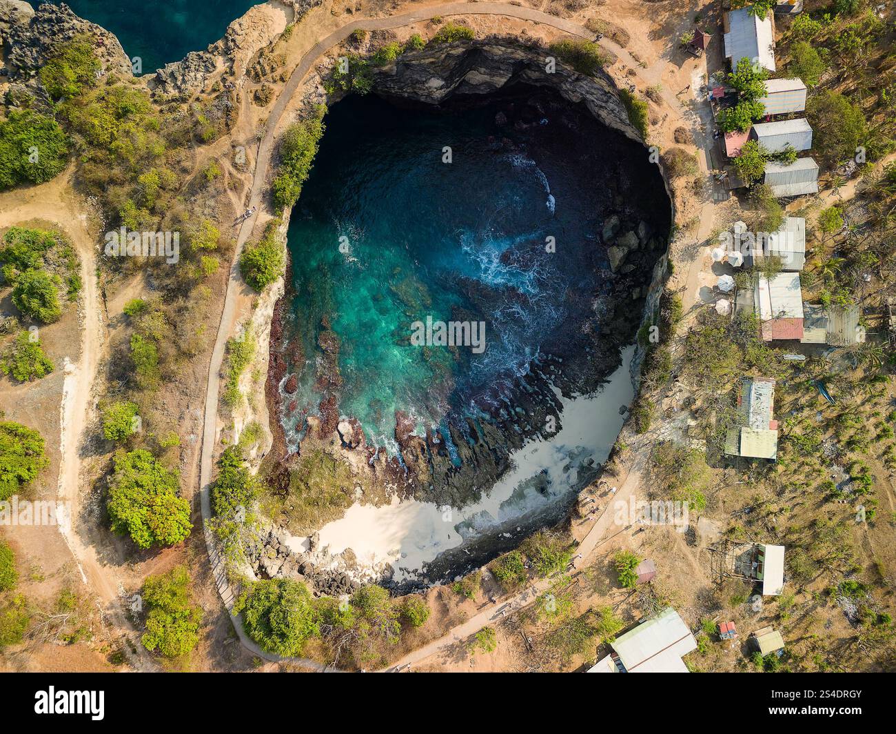 Birds eye view of a small beach and tropical ocean inside a sinkhole ...