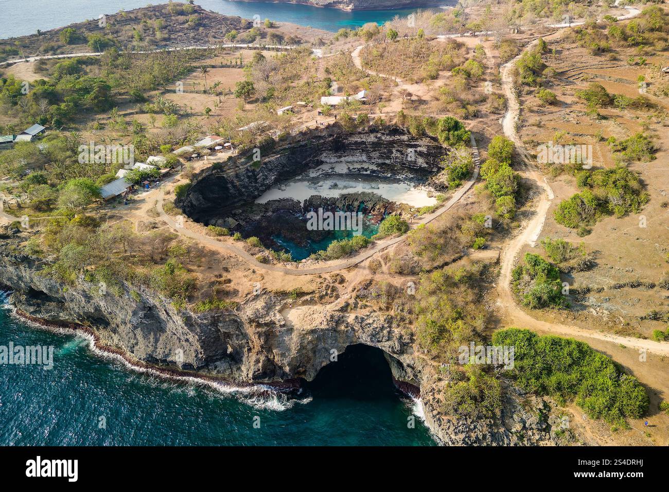 Aerial view of a tropical ocean and natural arch leading to a sinkhole ...