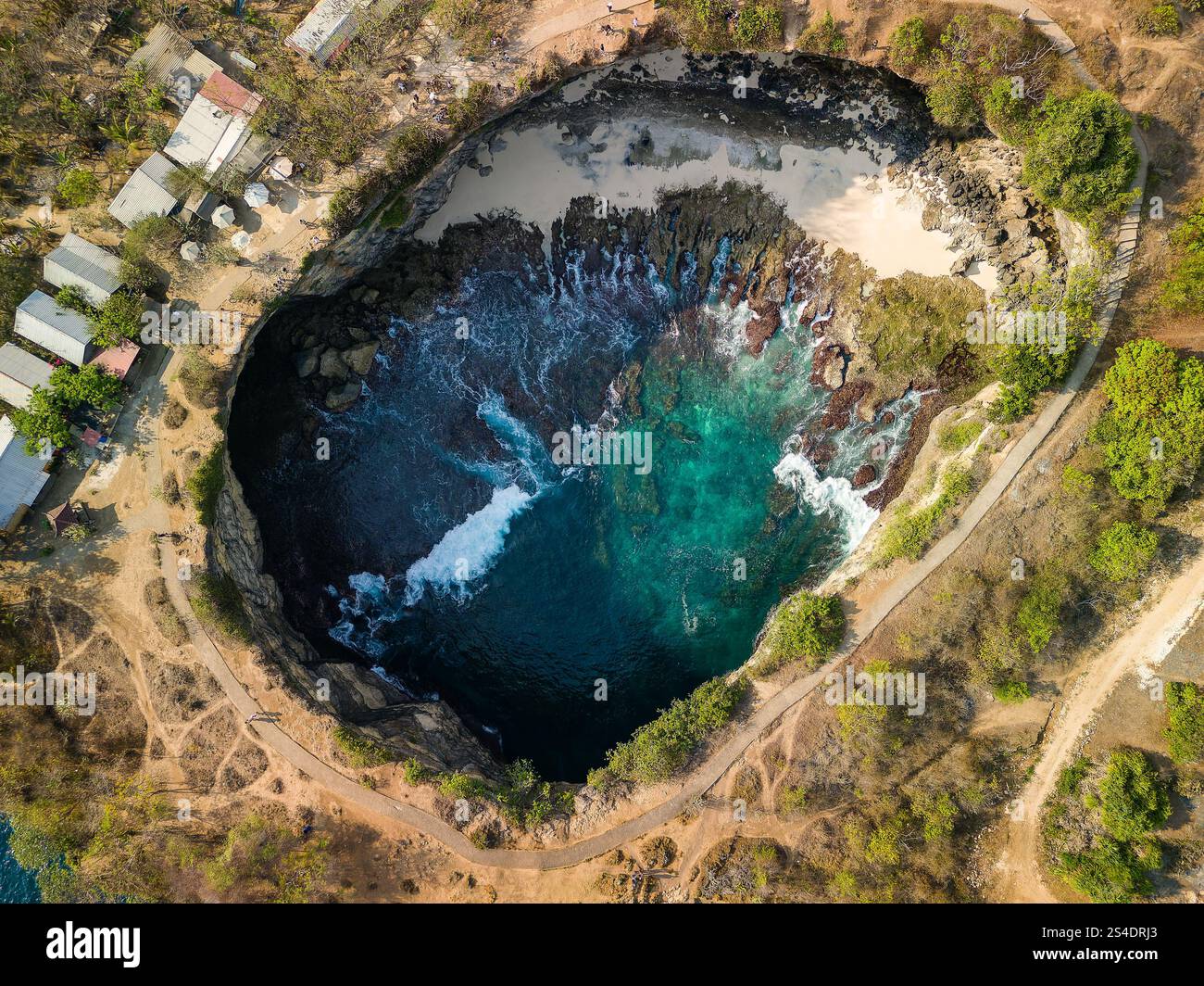 Birds-eye view of a sinkhole with small beach and tropical ocean waves ...