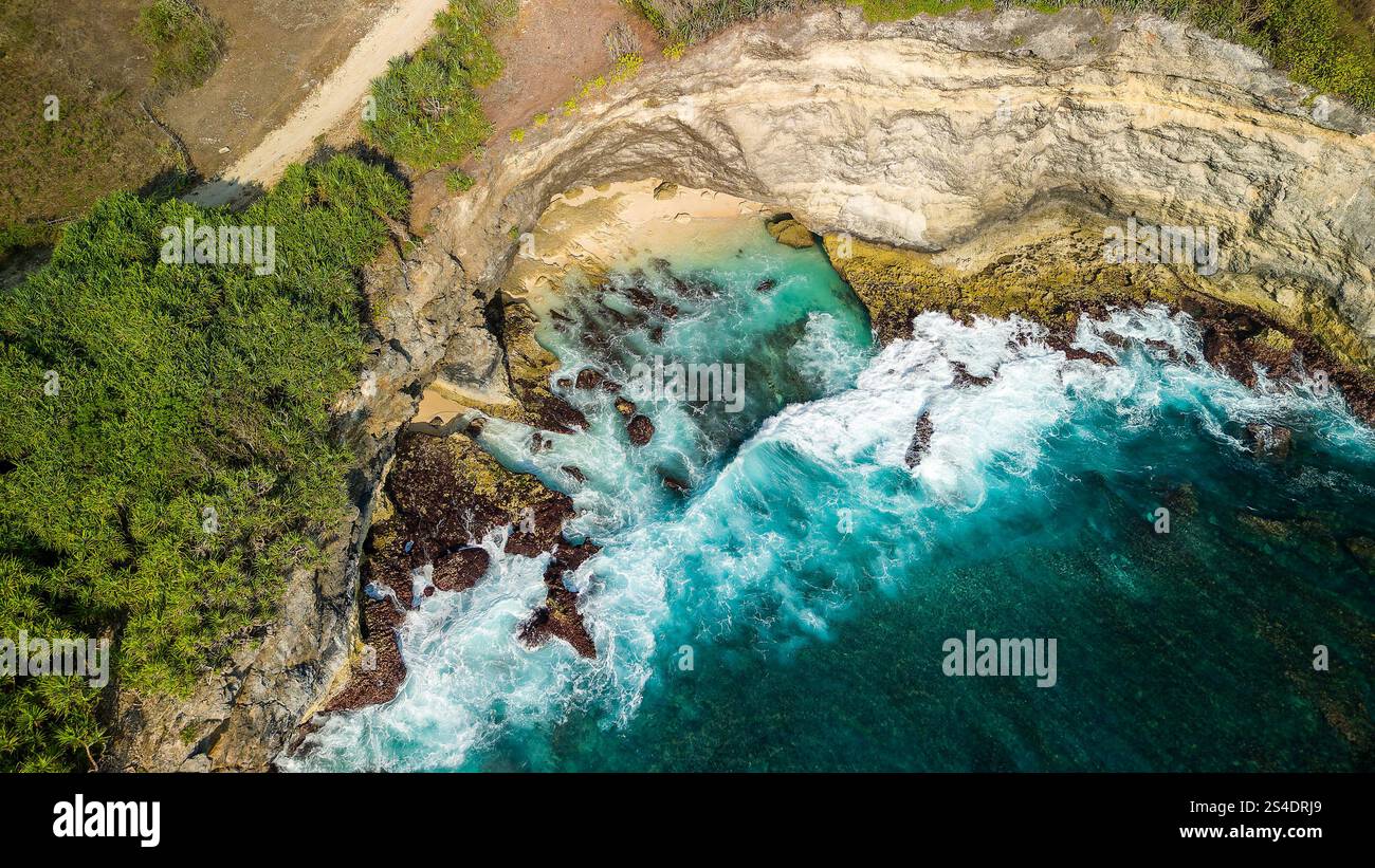 Top down view of ocean waves crashing into a dry, tropical coastline ...