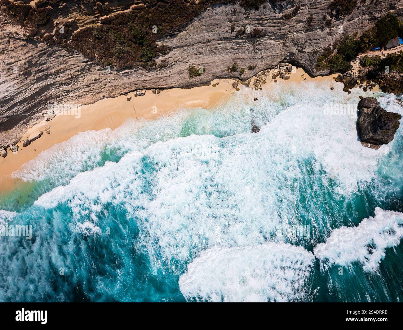 Birds eye view of ocean waves crashing against vertical cliffs and a ...