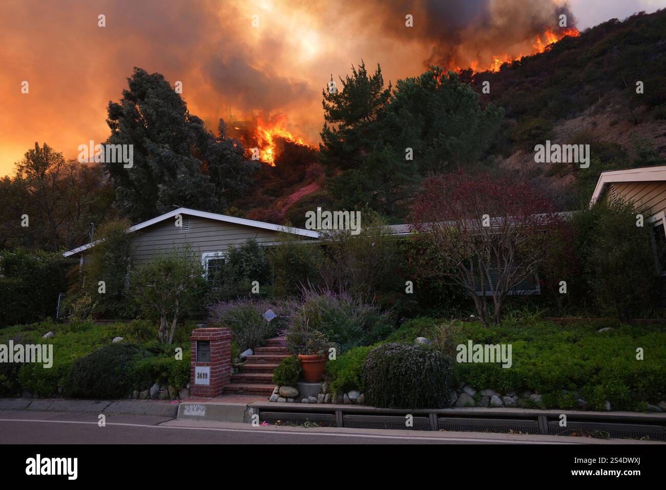 The Palisades Fire burns above a home in Mandeville Canyon, Saturday ...