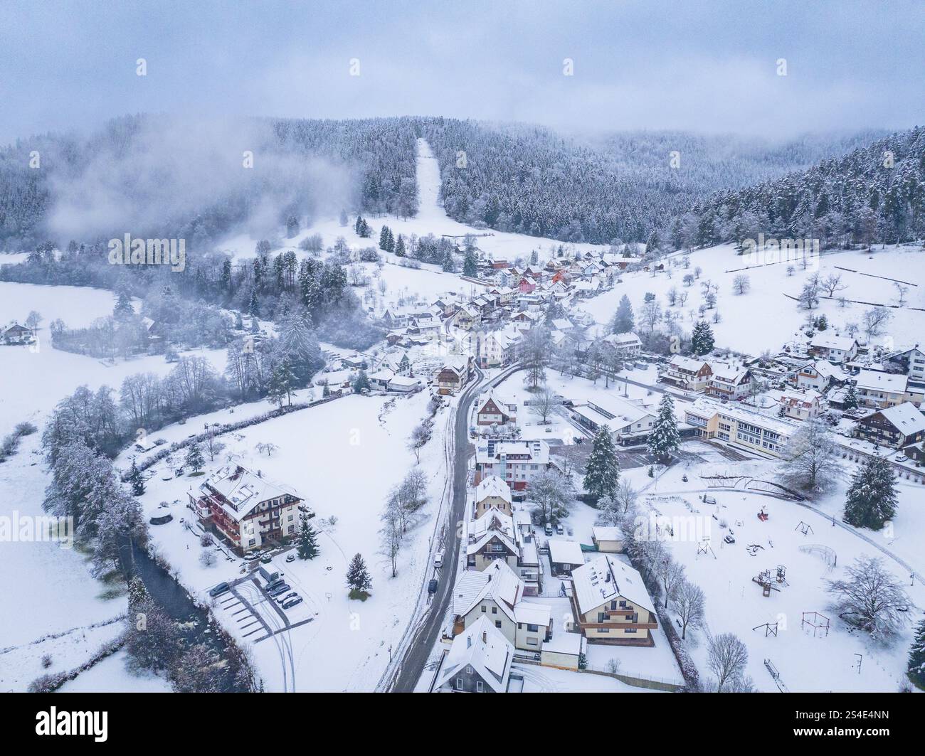 Rural winter landscape with snow-covered houses and hills ...