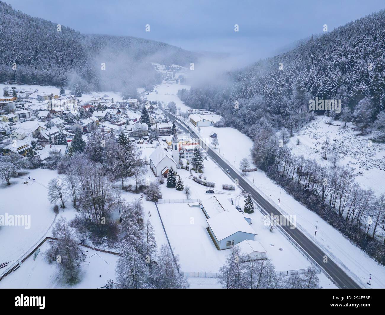 A snowy village with a main street surrounded by forest and hills ...