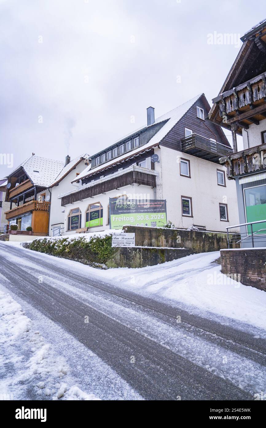 Snow-covered village street with a traditional house and opening sign ...