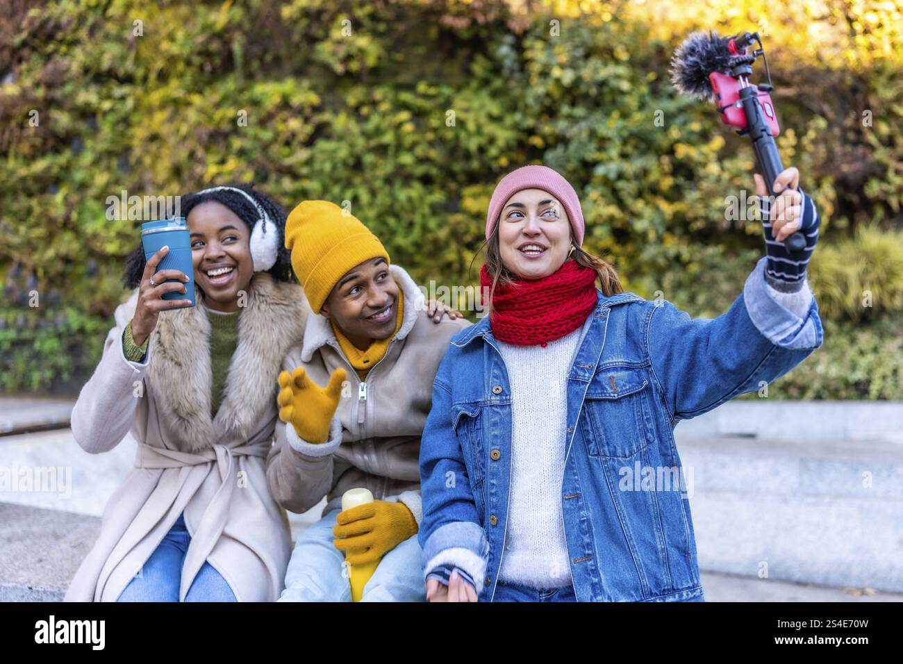 Three young content creators are filming a video blog outdoors in a ...