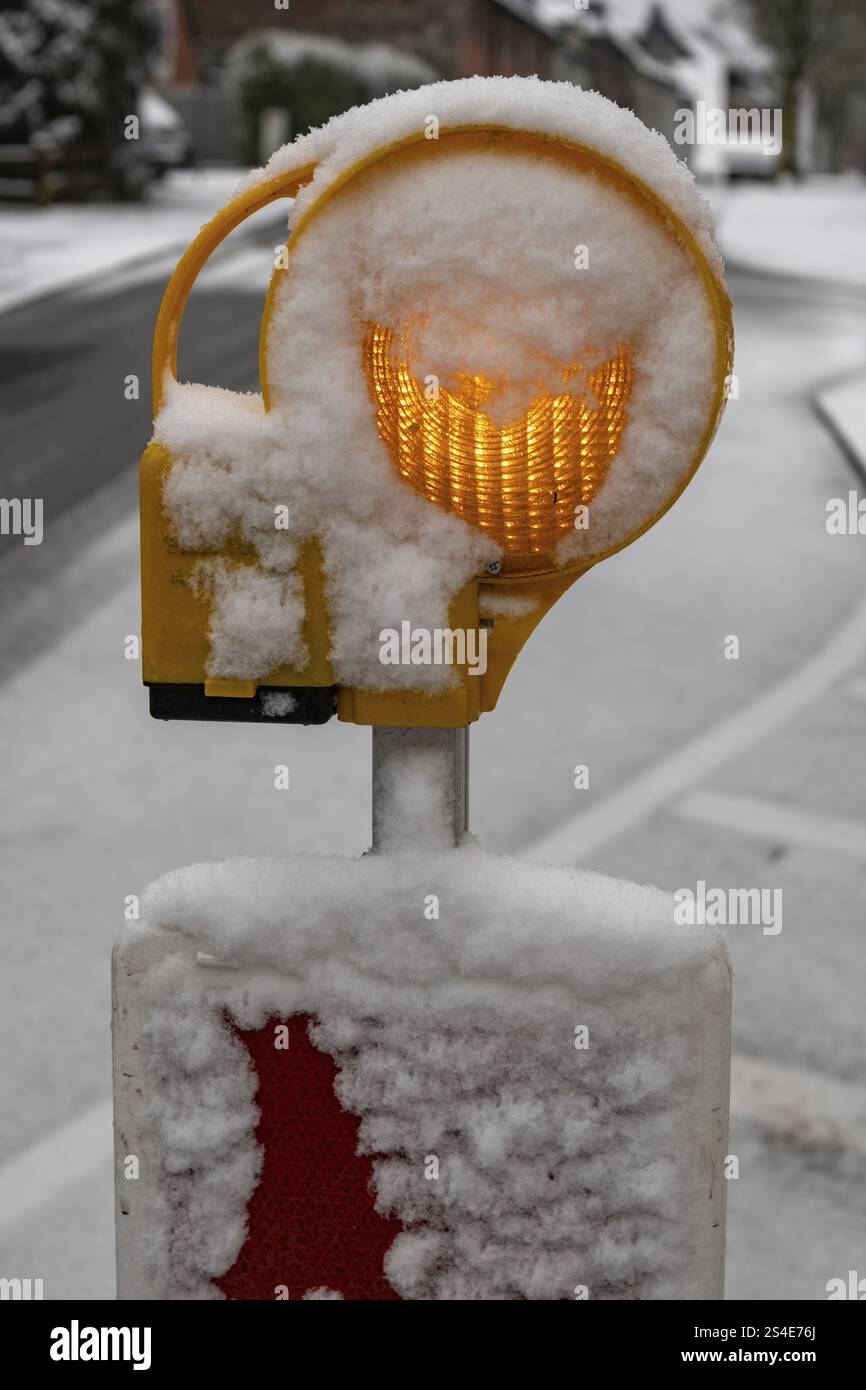 Flashing yellow warning light covered with fresh snow during winter ...