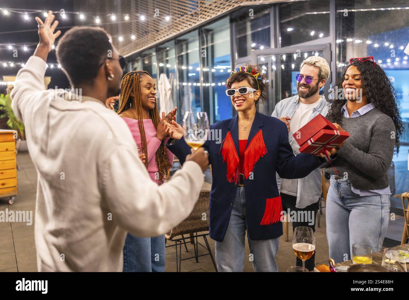 Multiracial friends celebrating surprise birthday party for a woman at ...