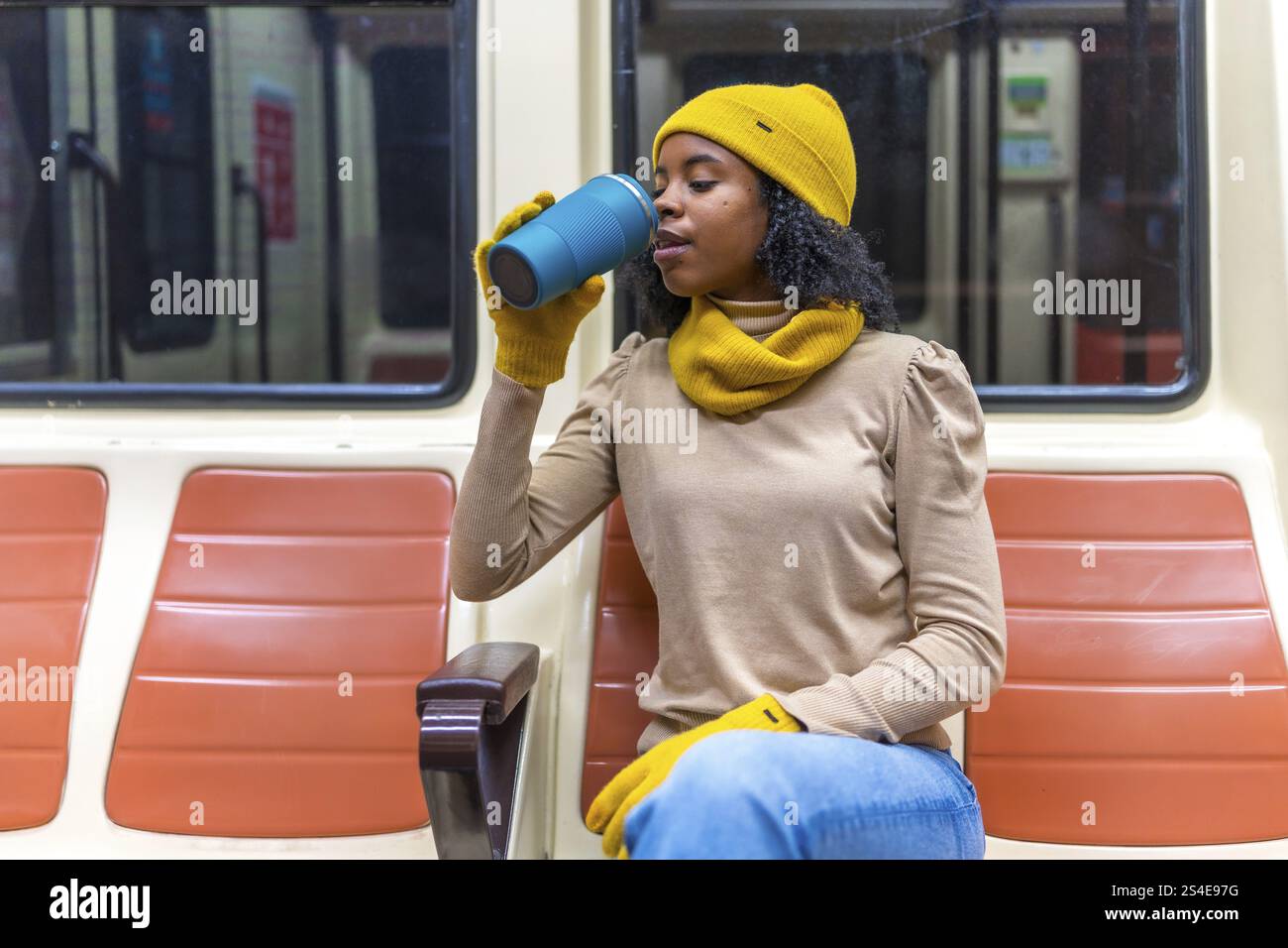 Young woman wearing winter clothes is sitting on a subway train ...