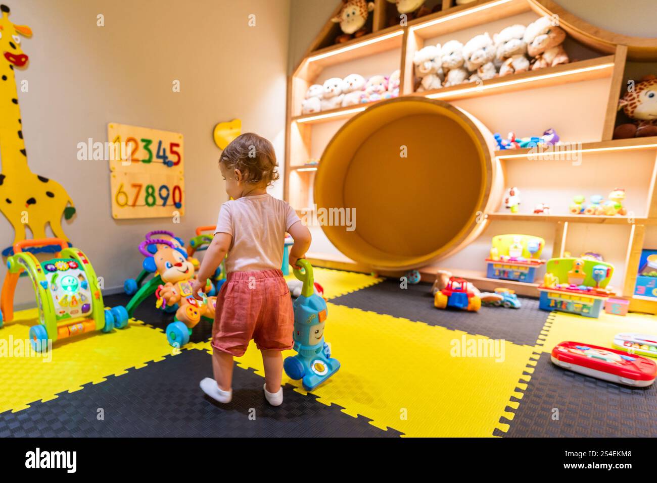 Curious child exploring pretend cleaning with a toy vacuum cleaner in a ...