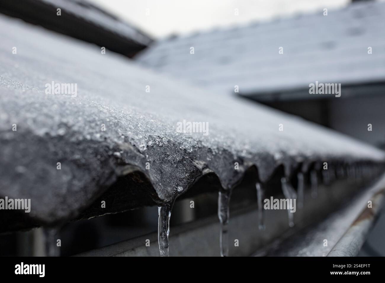 melting snow from a undulated roof with small icicles perspective, soft ...