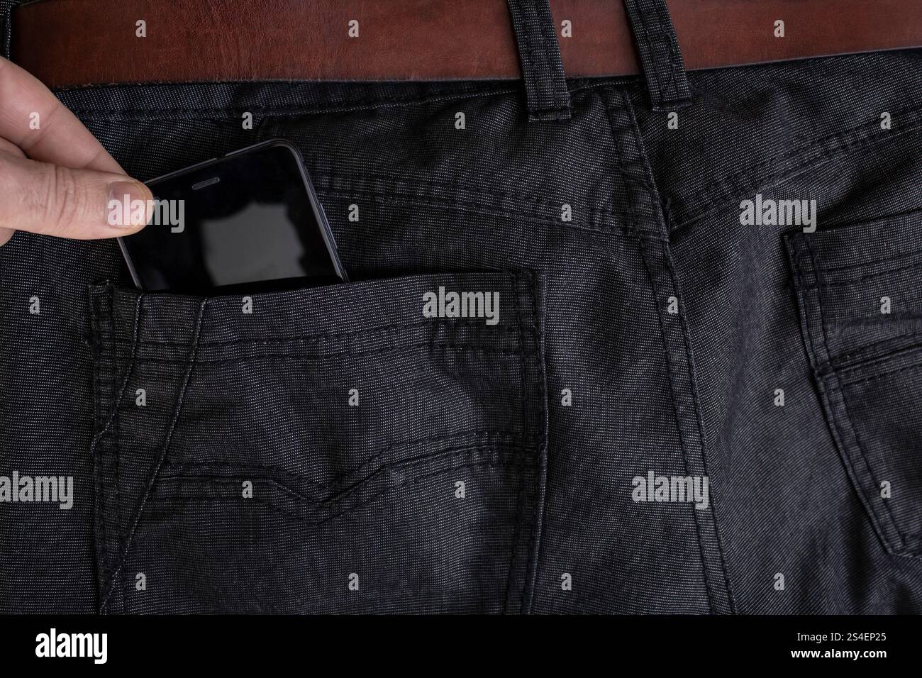 Male hand pick pocketing a smart phone from black jeans back pocket ...