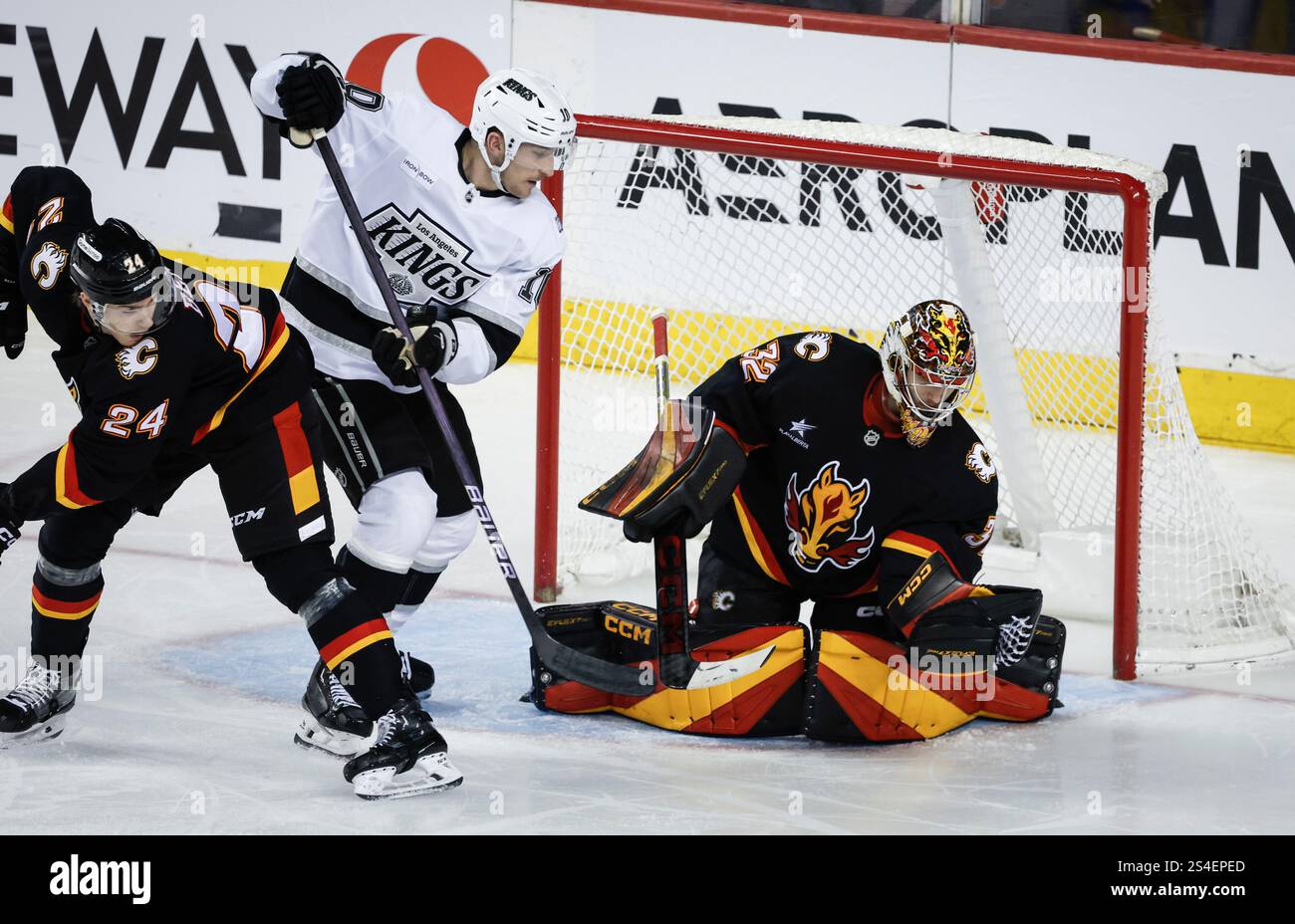 Los Angeles Kings' Tanner Jeannot, center, is checked by Calgary Flames ...