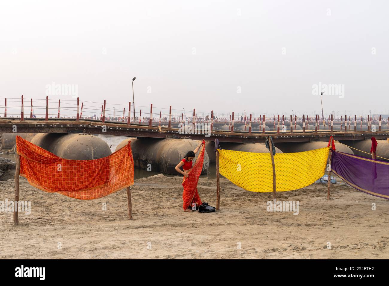 A Hindu woman devotee adjusts her saree as she changes after taking ...