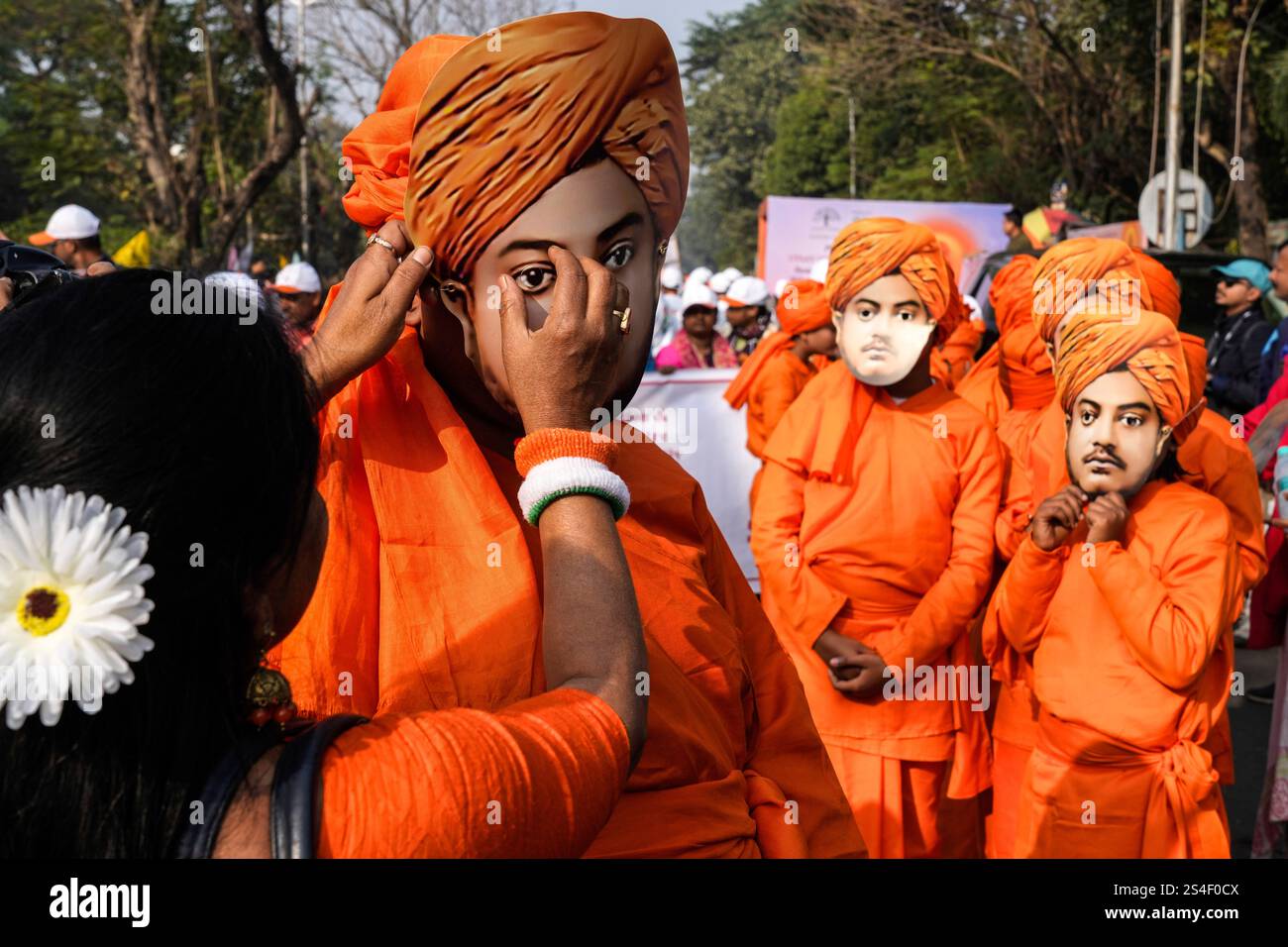 A volunteer fixes a mask on a child dressed like Swami Vivekananda, a ...