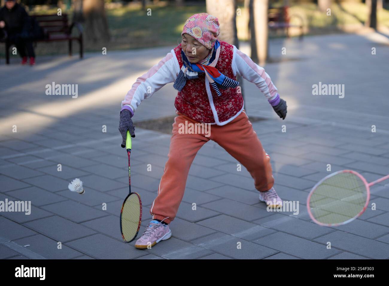 A woman plays badminton during a cold morning at a park in Beijing ...