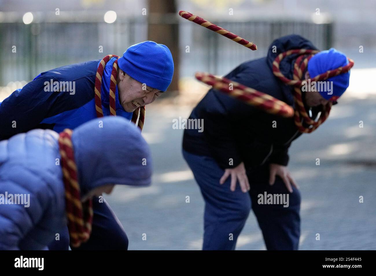 Men try to catch cloth rings using their head as families spend their ...