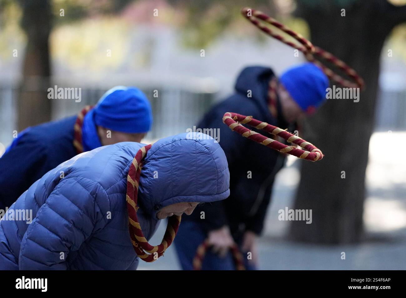 Men try to catch cloth rings using their head as families spend their ...