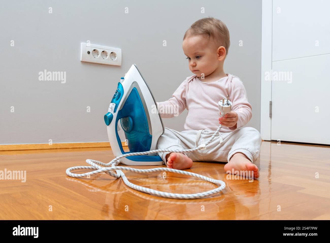 Curious baby engaged with an iron plug, illustrating the importance of ...