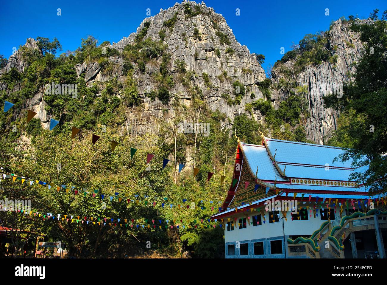 Buddhist monastery, decorated with flags, at the foot of a towering ...