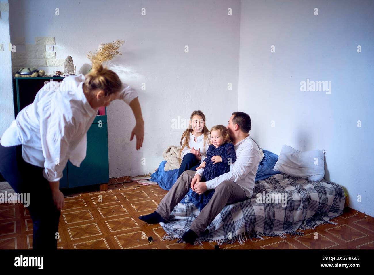 a family with toddler and teenager playing games, laughing, clapping ...