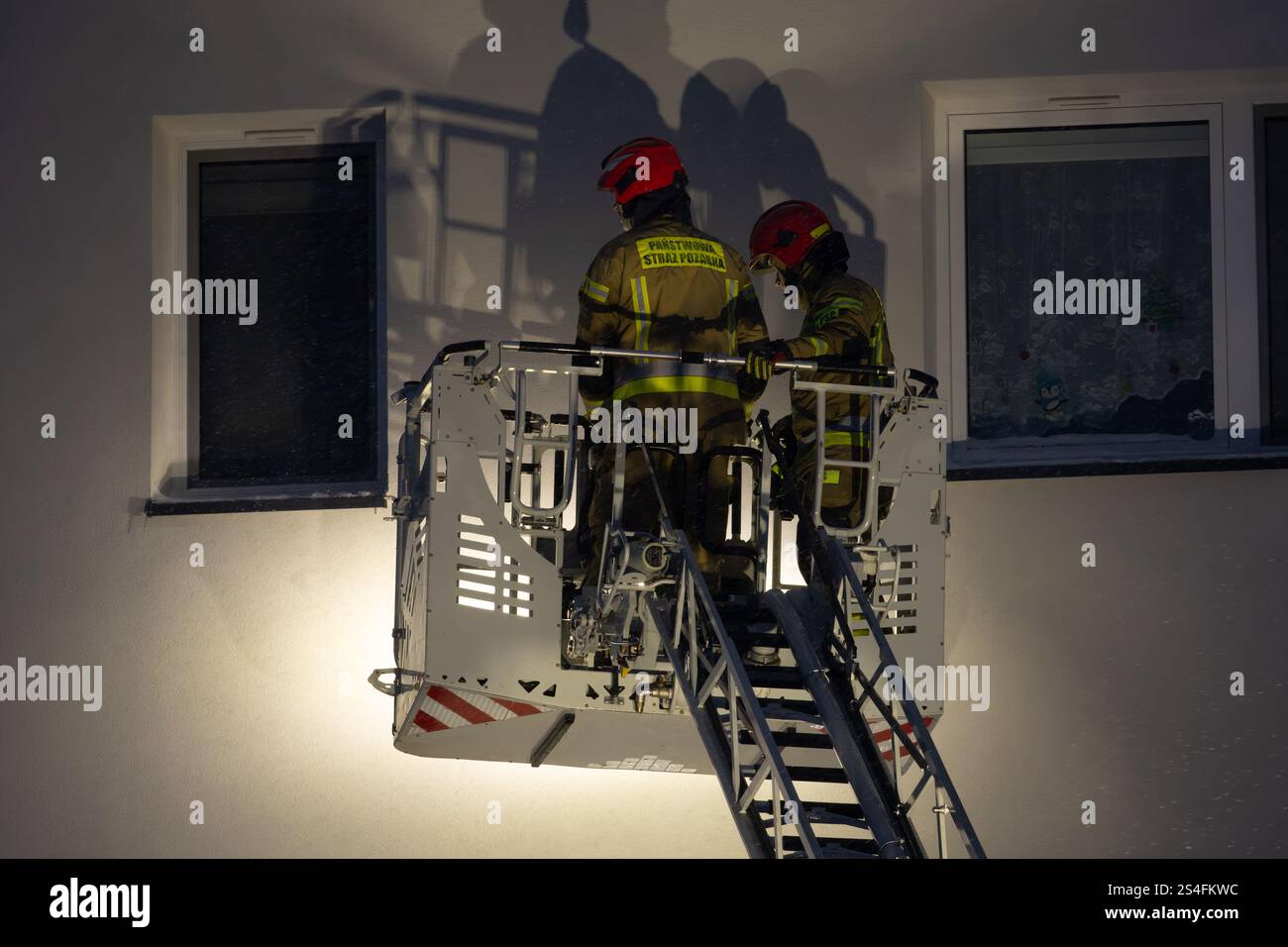 Two firefighters in a basket mounted on a high ladder look into the ...